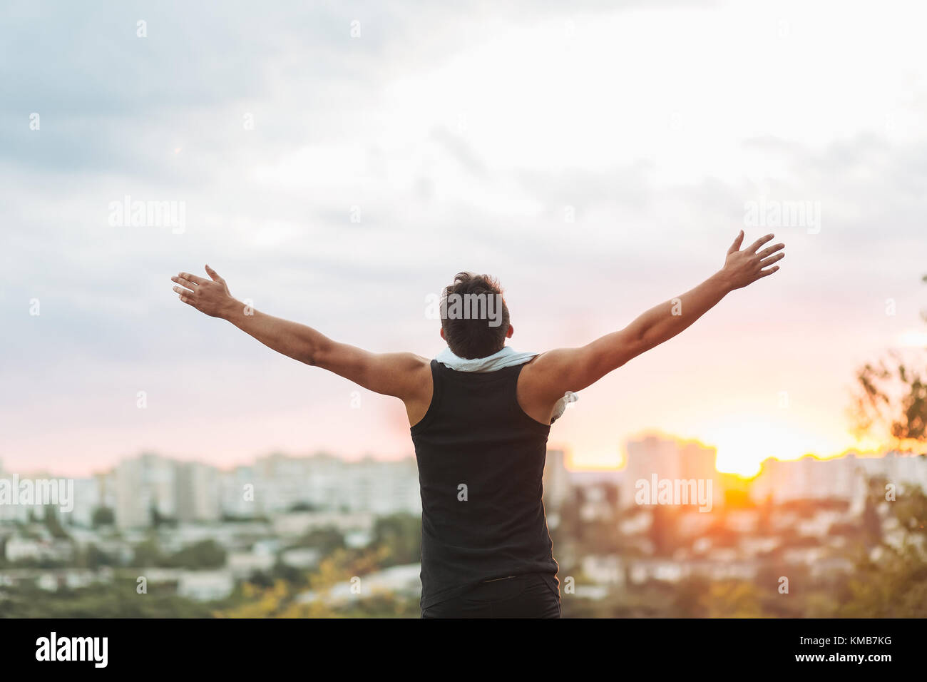 Young man raising hands over sunset sky after training Stock Photo - Alamy