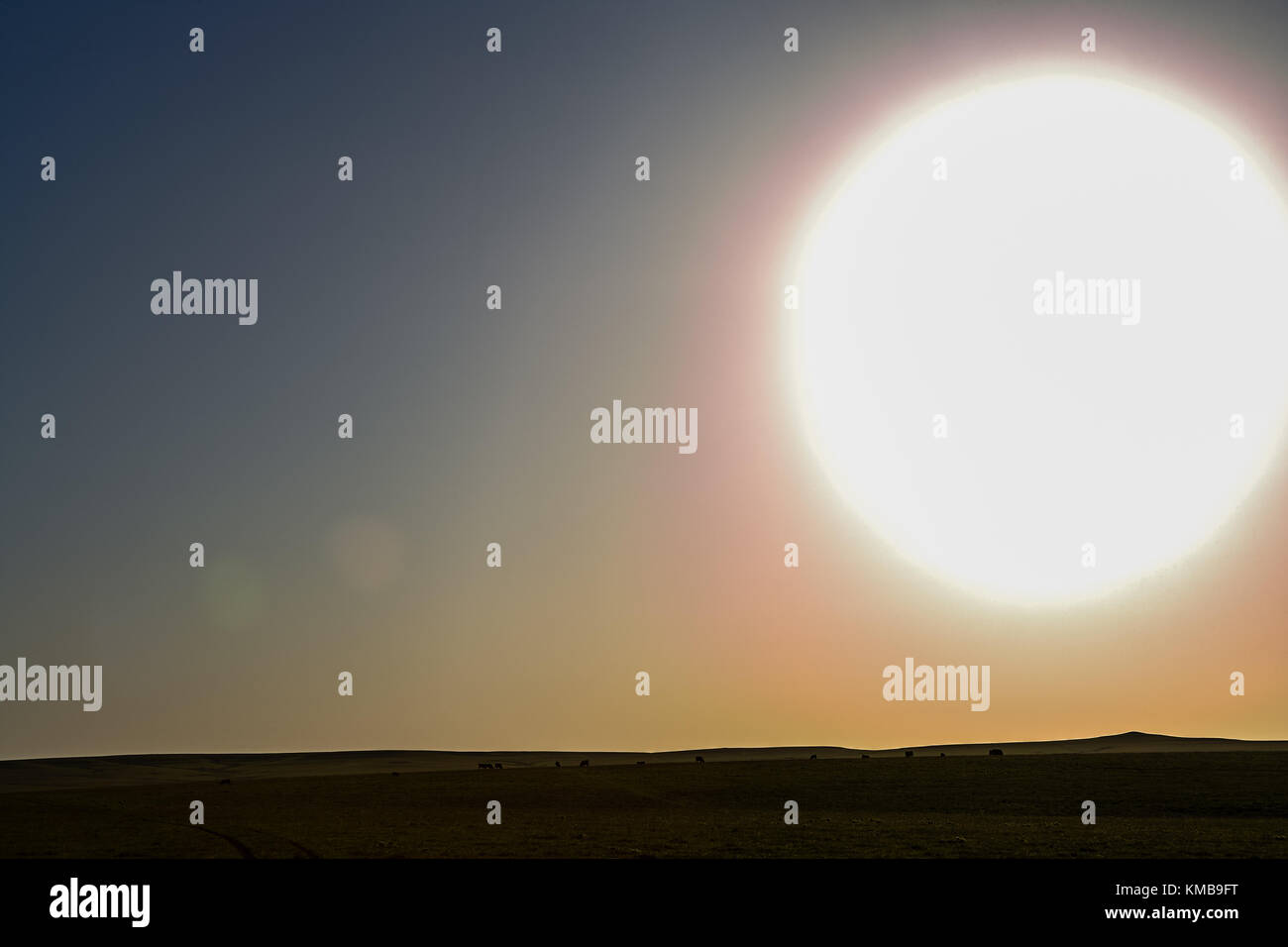 Big overexposed ball of sun in the sky over dark and smooth terrain ...