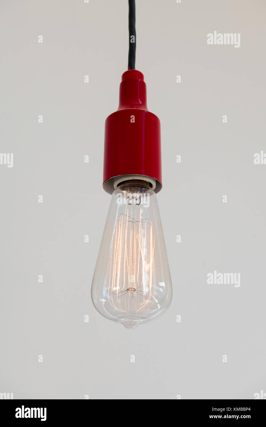 A light bulb with filaments hanging from a red fixture Stock Photo - Alamy