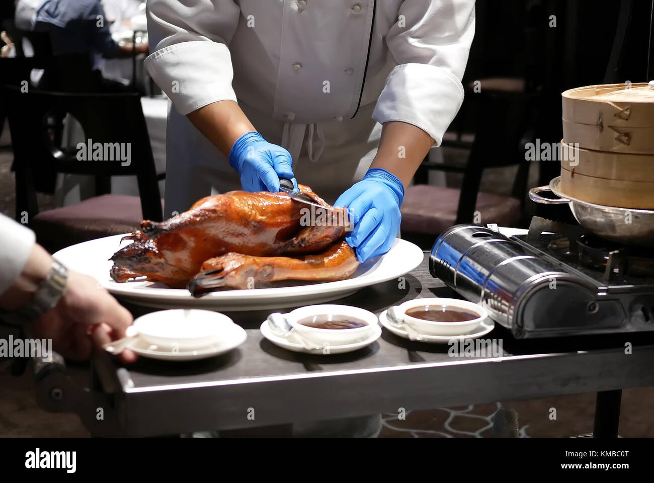 Motion of chef cutting roasted duck into a plate for customer inside ...