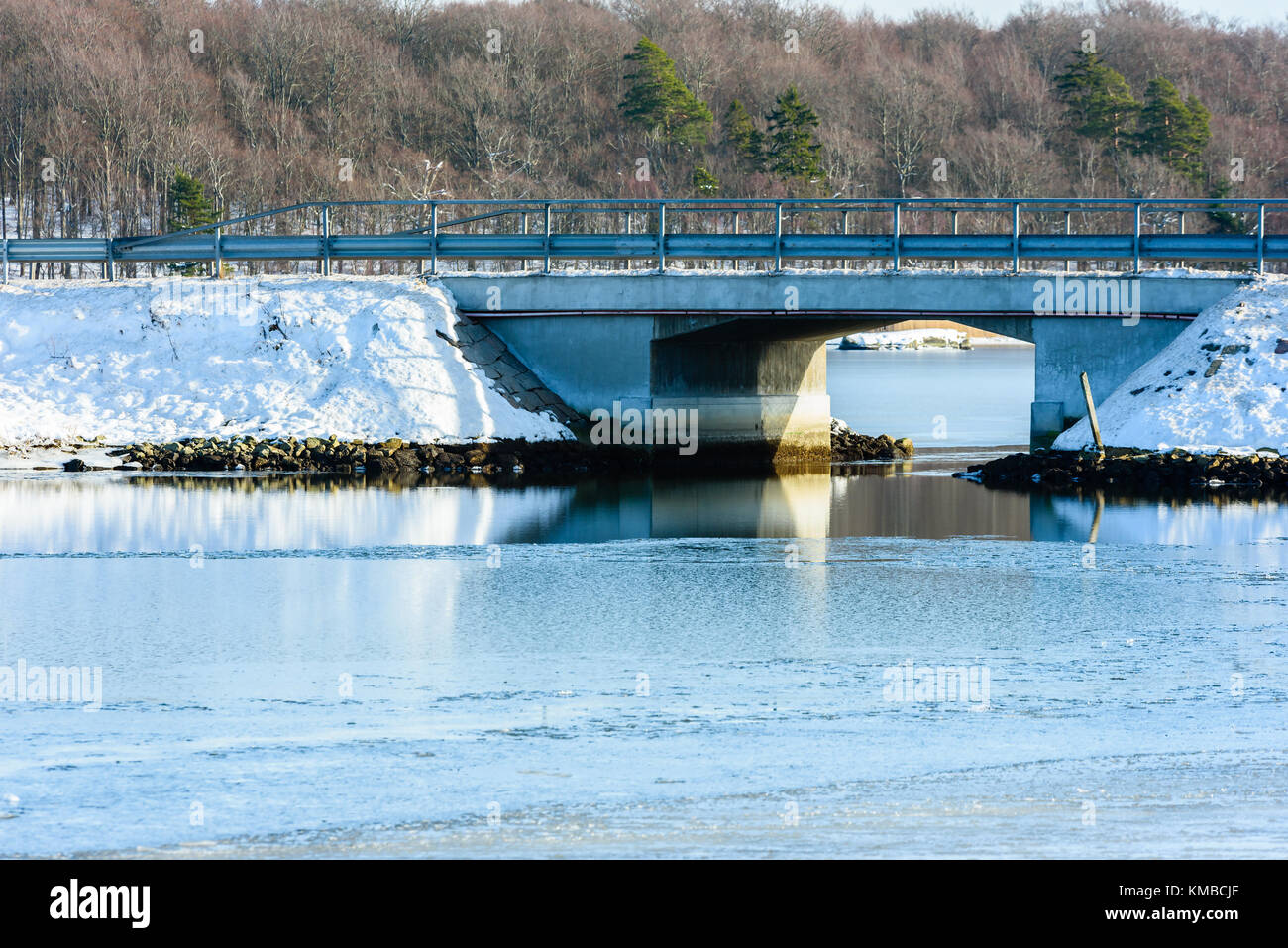 Open water flow under a small viaduct or bridge and thin ice cover the ...