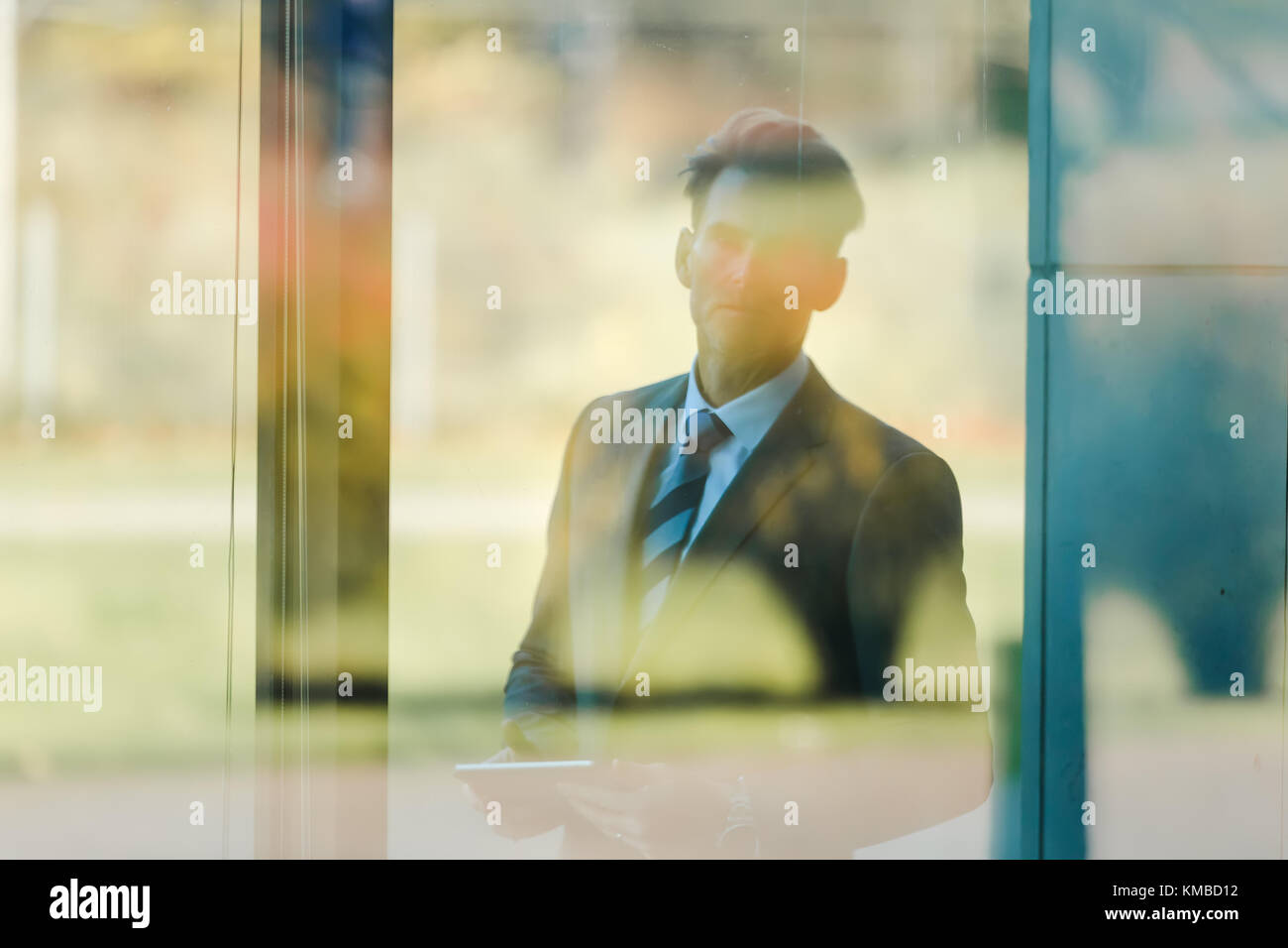 businessman in front of an office building seen through the windows ...