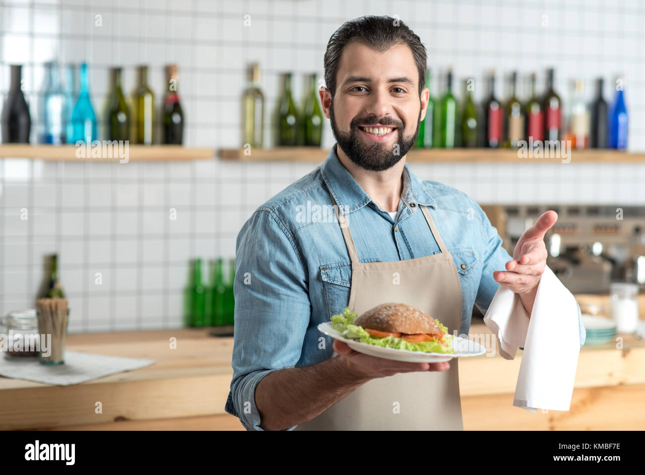 Pleasant positive waiter smiling while showing a tasty lunch Stock ...