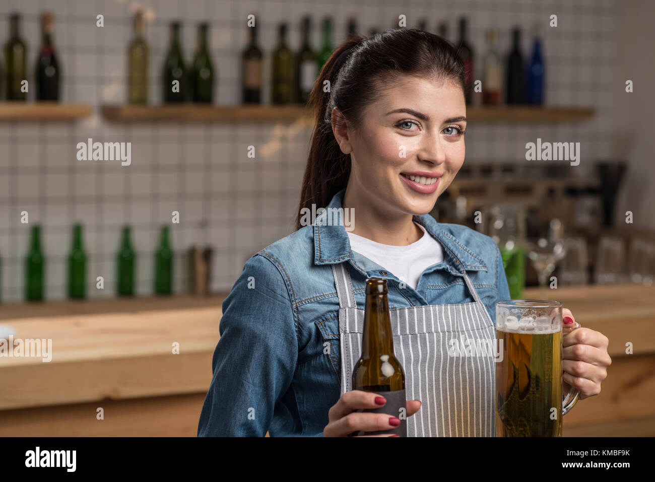 Lovely cheerful waitress standing with beer and smiling kindly Stock ...