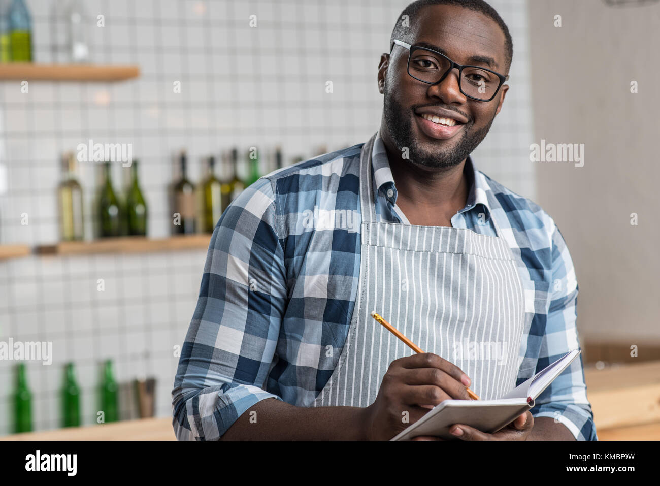 Smiling positive waiter standing with a notebook and writing Stock ...
