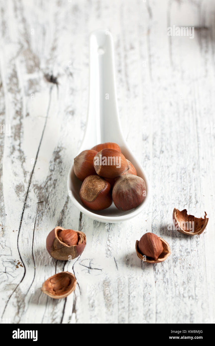 Whole and chopped hazelnuts on white wooden table Stock Photo - Alamy