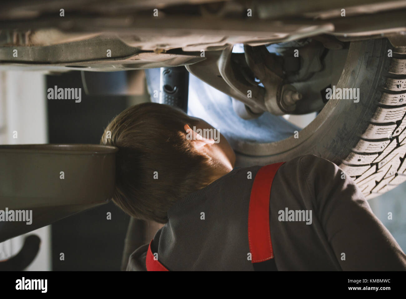 Mechanic unscrewing parts of automobile's bottom under lifted car Stock ...