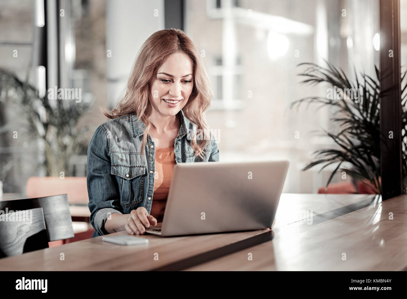 Smart young woman smiling and looking at her laptop Stock Photo - Alamy