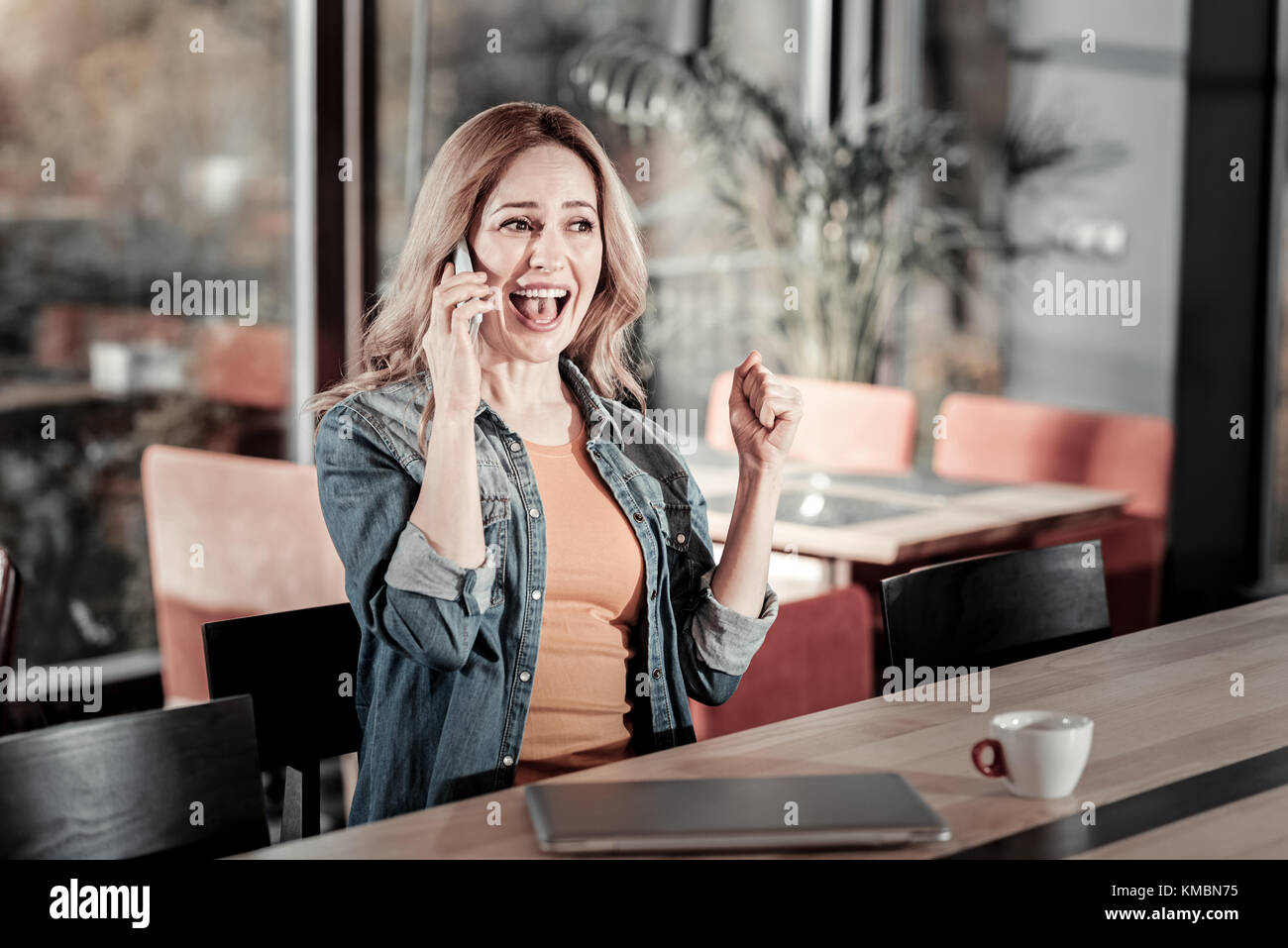 Emotional young woman looking excited while talking on the phone Stock ...