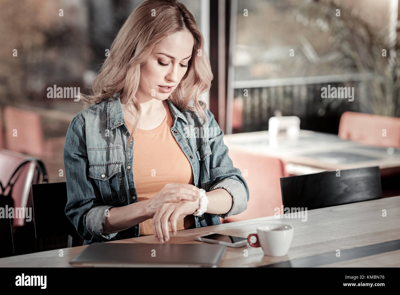 Worried young woman looking at her watch while waiting for a friend ...