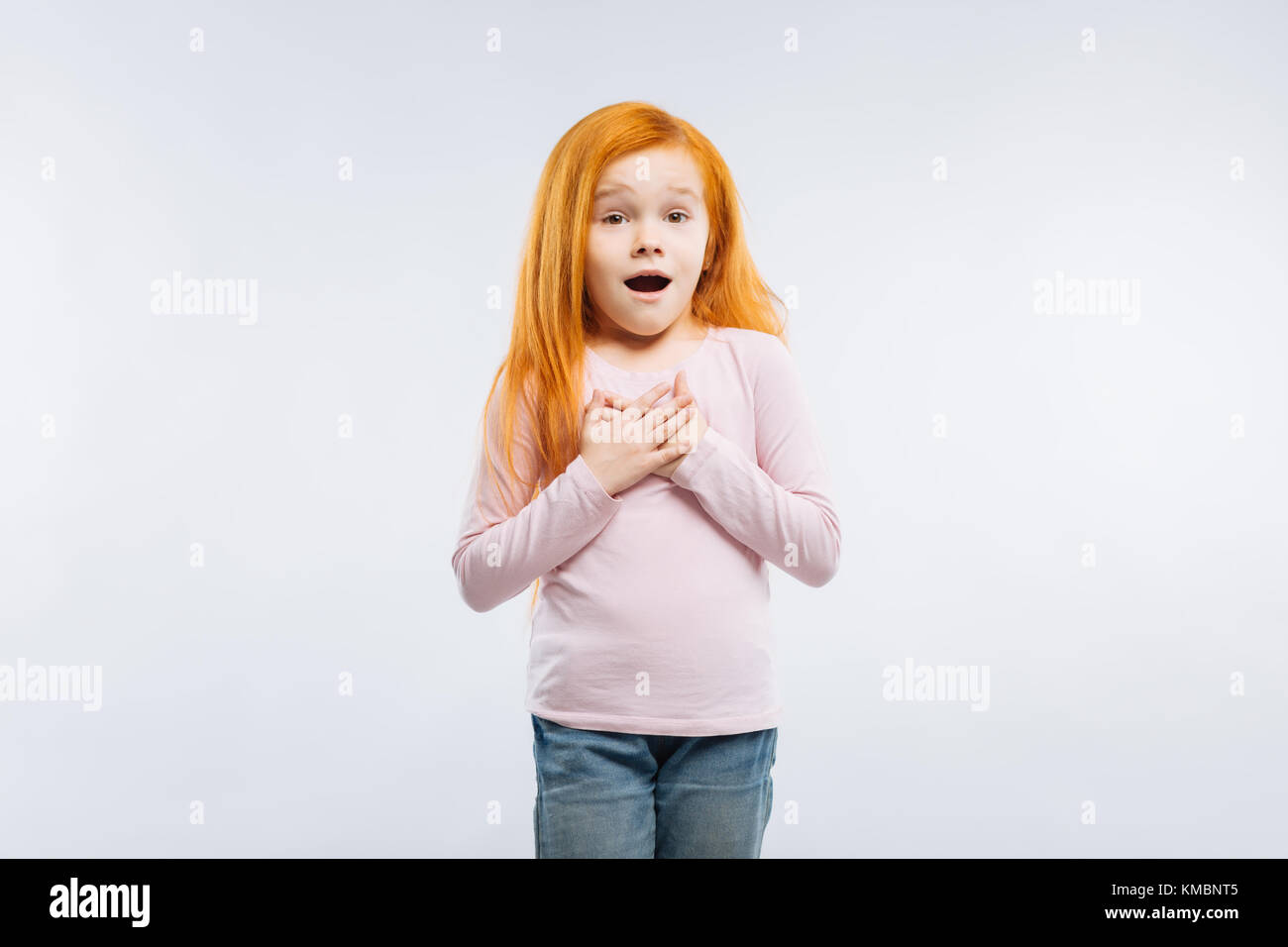 Surprised kid putting hands on her chest Stock Photo - Alamy