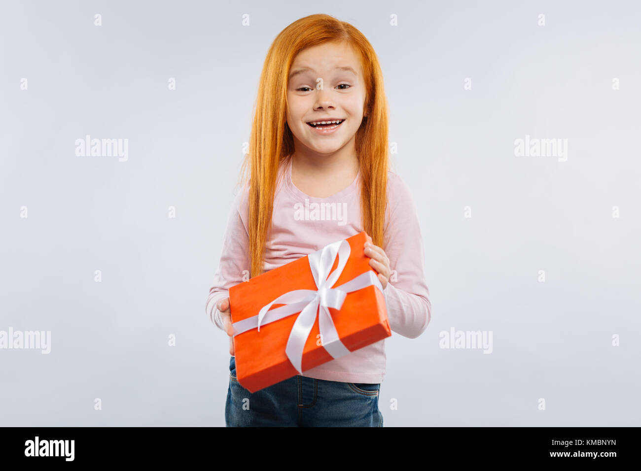 Positive delighted girl demonstrating gift box Stock Photo - Alamy