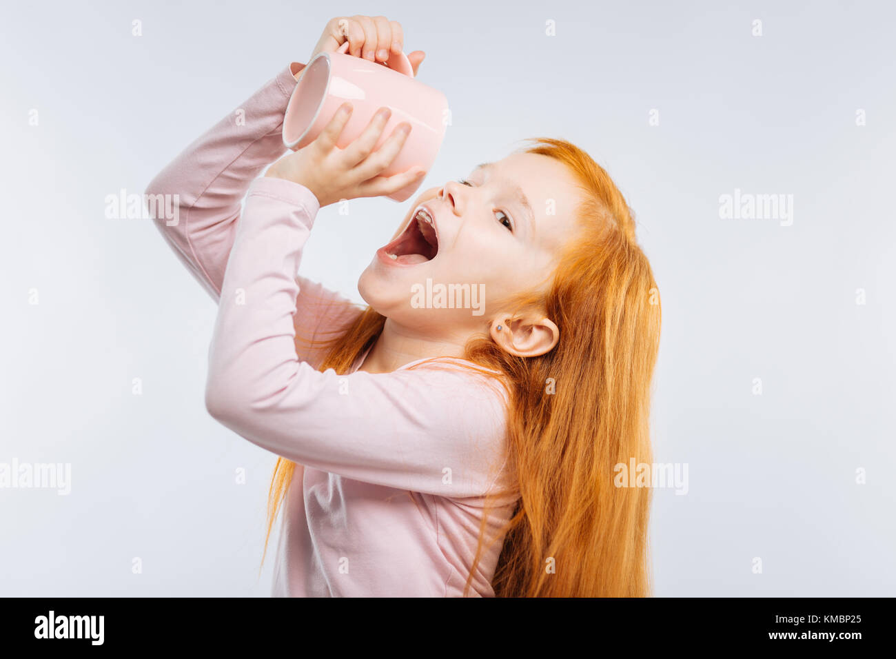 Playful girl raising her cup Stock Photo - Alamy
