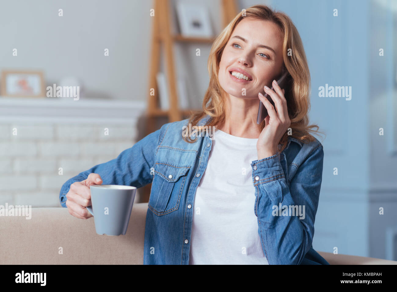 Cheerful young woman talking on the phone while drinking tea Stock ...