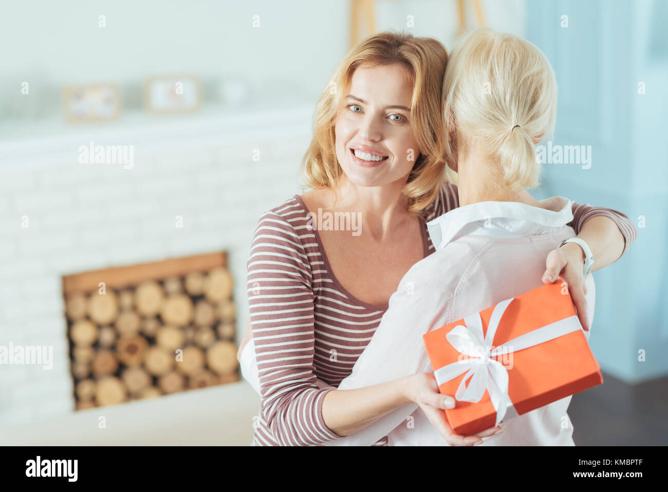 Beautiful young woman holding a present while greeting her relative ...