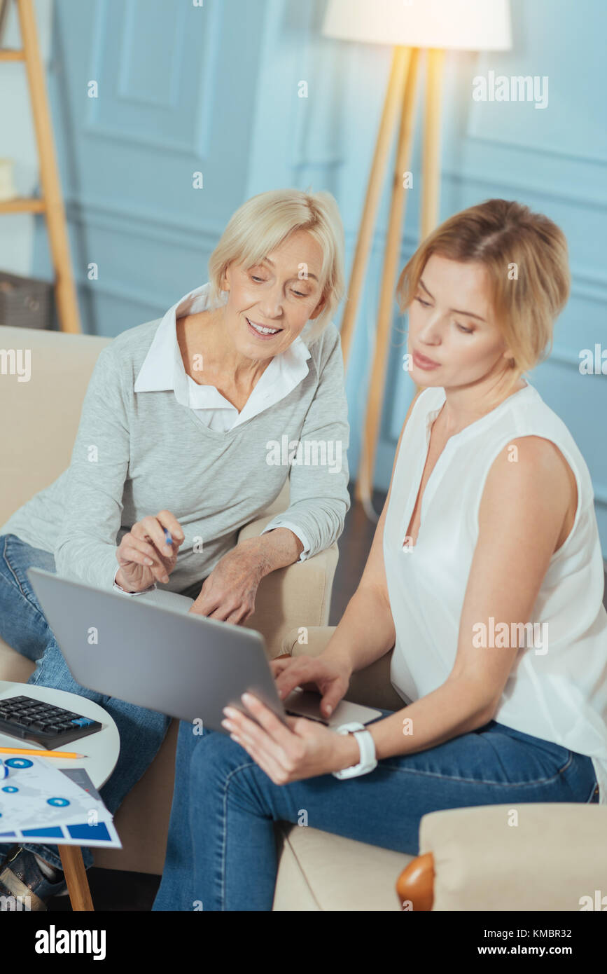 Cheerful aged woman looking at the laptop and smiling kindly Stock ...