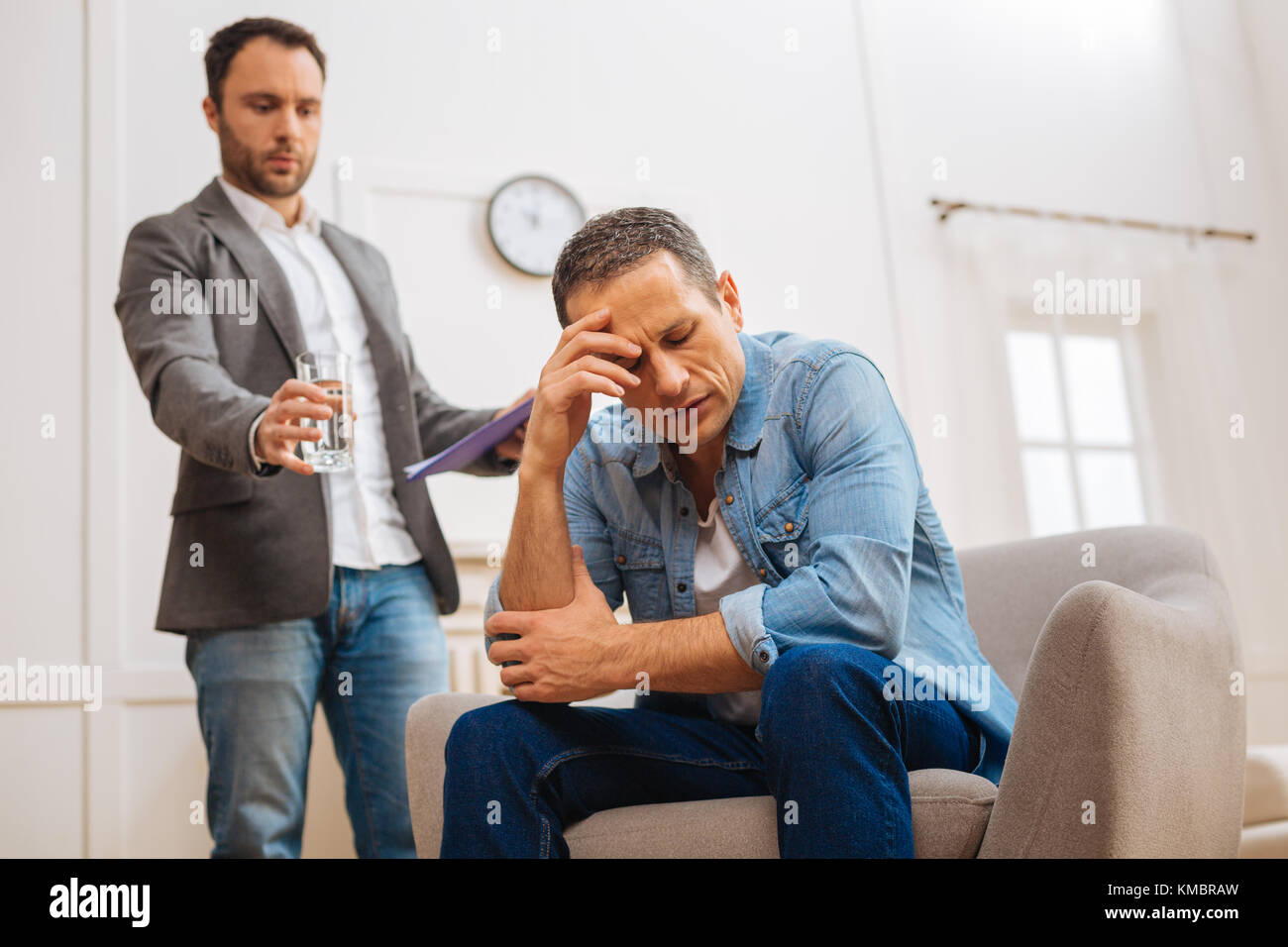 Careful male psychologist proposing water to patient Stock Photo - Alamy