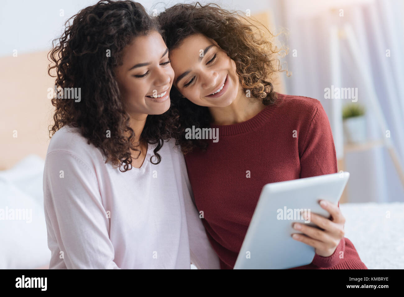 Loving female siblings hugging while looking at tablet computer Stock ...
