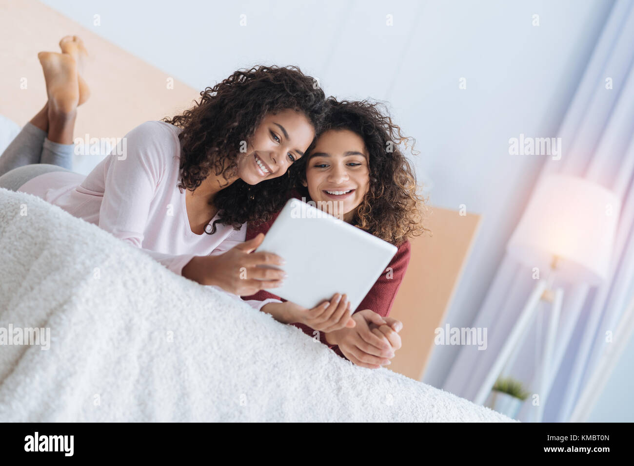 Smiling curly haired siblings using touchpad together Stock Photo - Alamy
