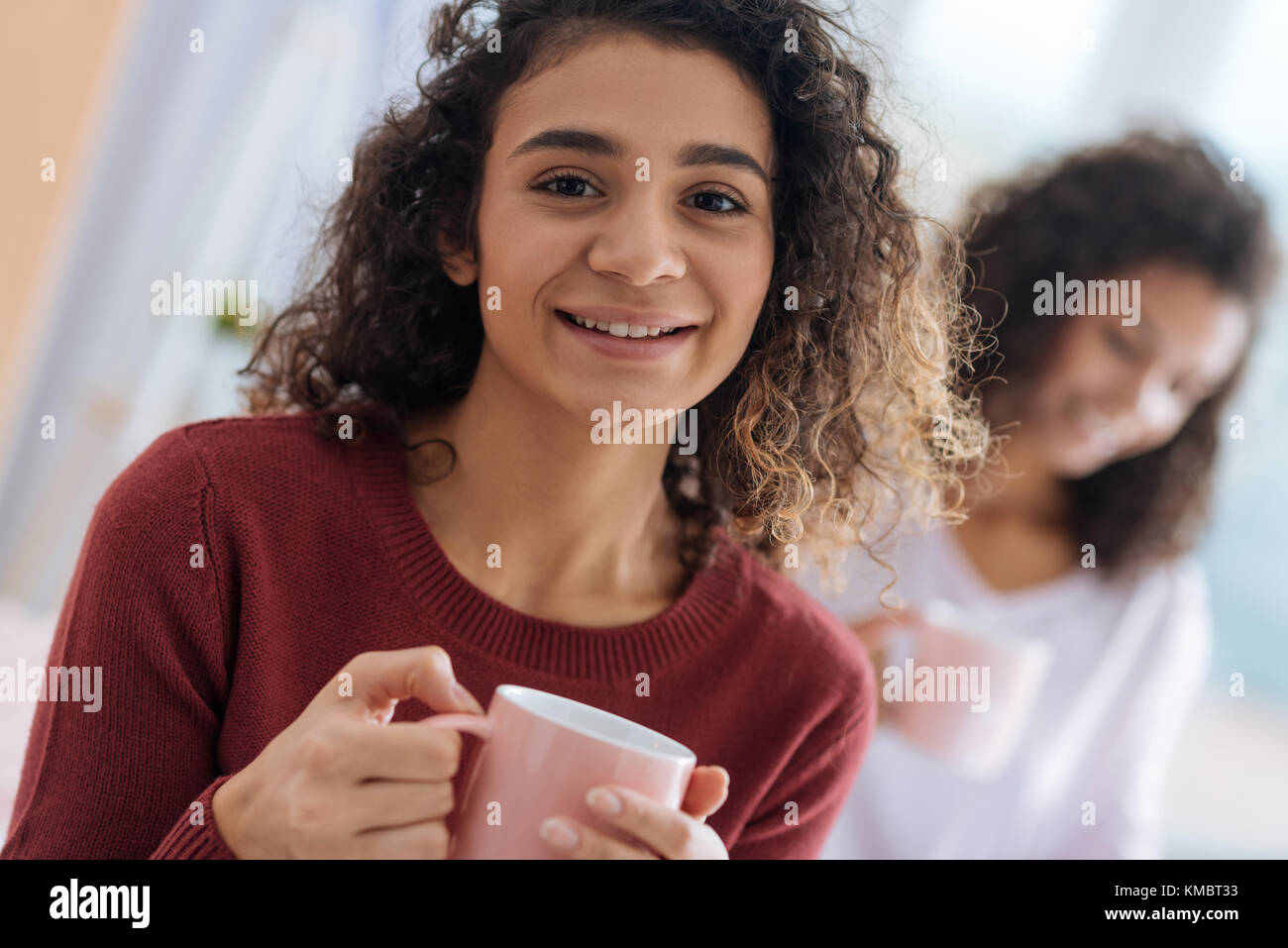 Adorable young lady smiling into camera while drinking tea Stock Photo ...