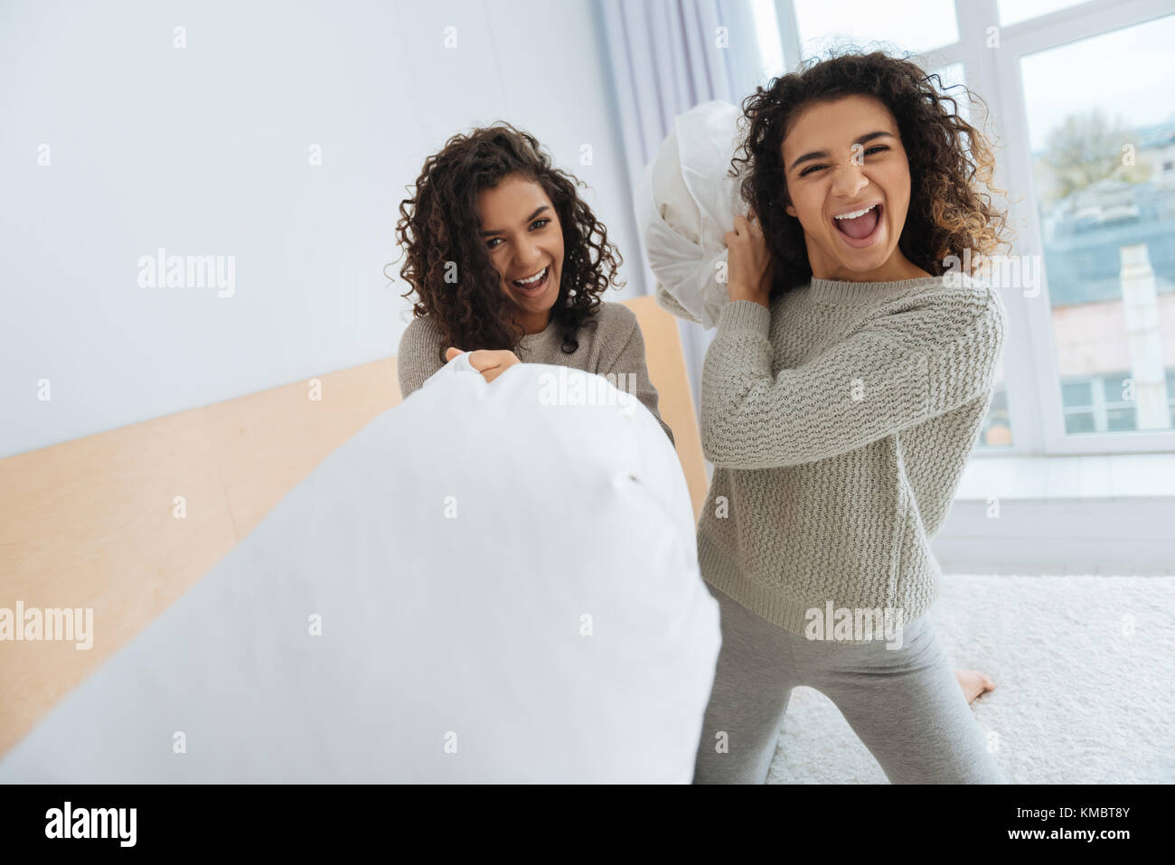 Full of energy friends fighting with pillows Stock Photo - Alamy