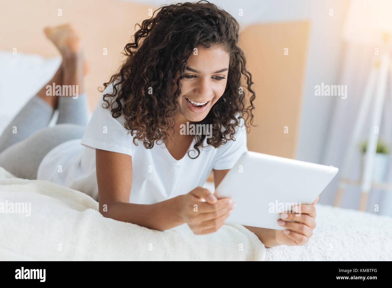 Extremely happy girl smiling while looking at tablet computer Stock ...