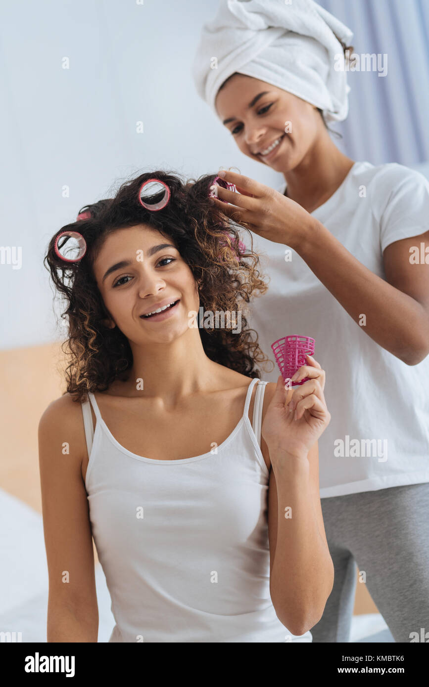 Cheerful young ladies getting ready and curling hair at home Stock ...