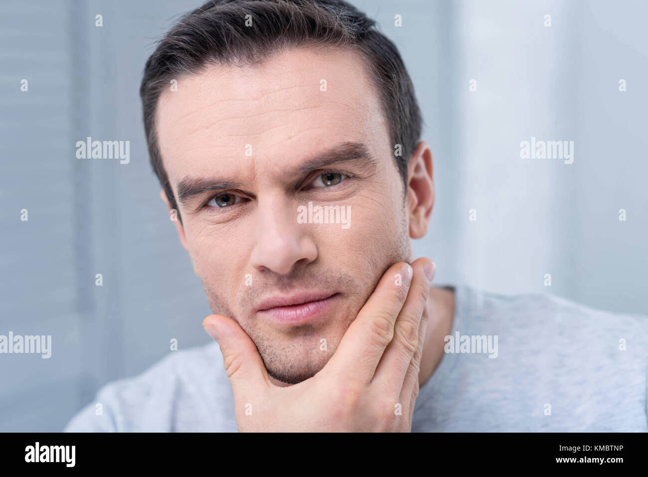 Adorable sweet man scratching his chin Stock Photo - Alamy