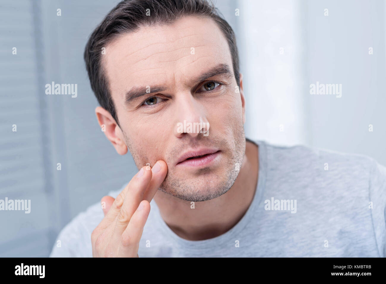 Tranquil confident man examining his face Stock Photo - Alamy