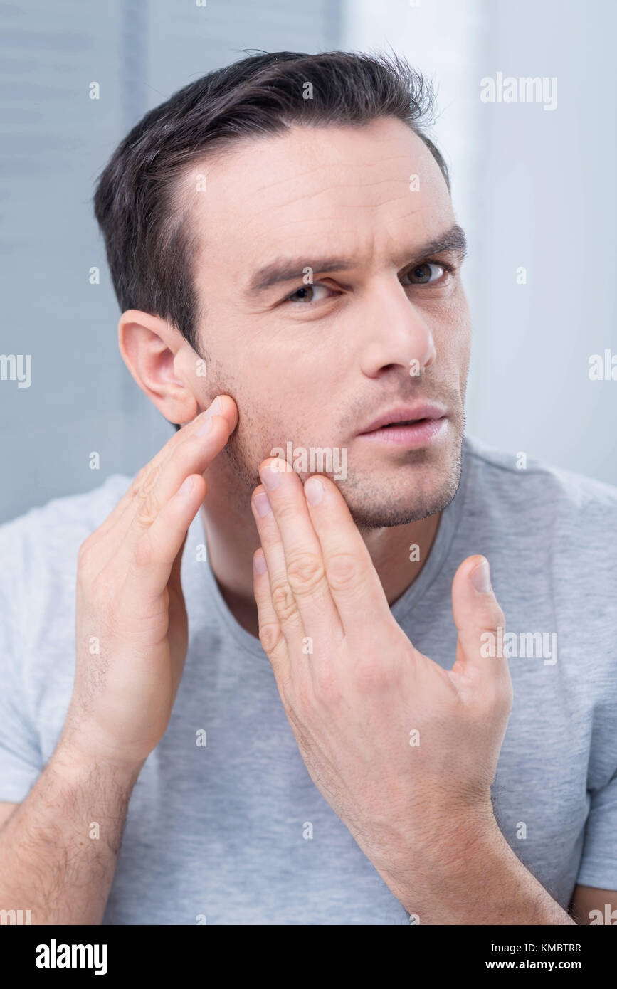 Worried focused man scrutinizing his face Stock Photo - Alamy