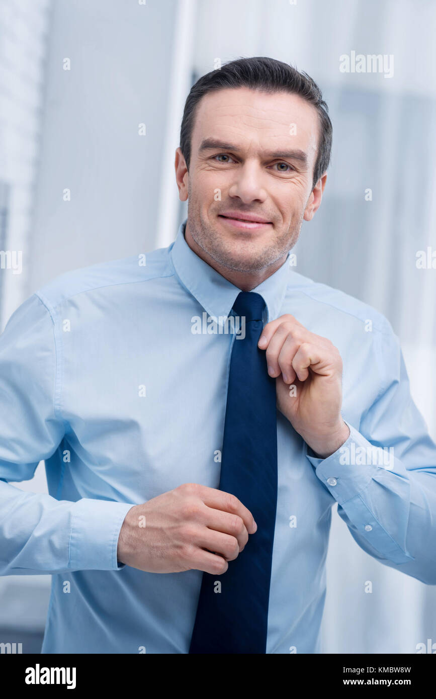 Cute nice man checking his tie Stock Photo - Alamy