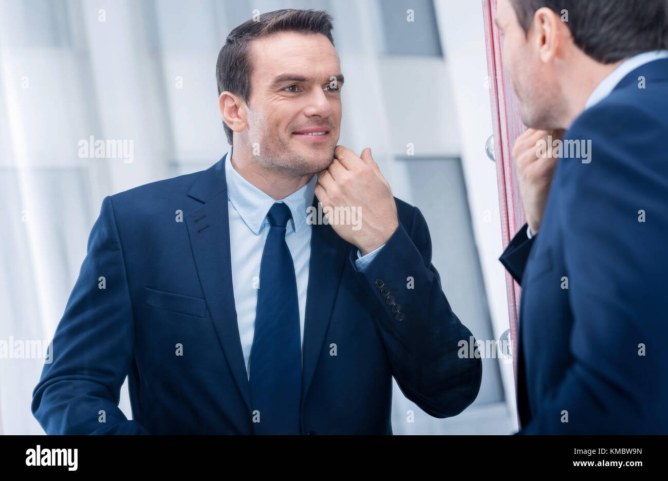 Pleasant cute man touching his head Stock Photo - Alamy