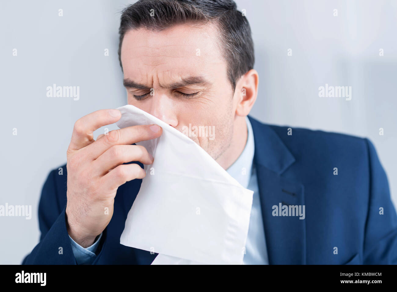 Cute pleasant man sneezing Stock Photo - Alamy