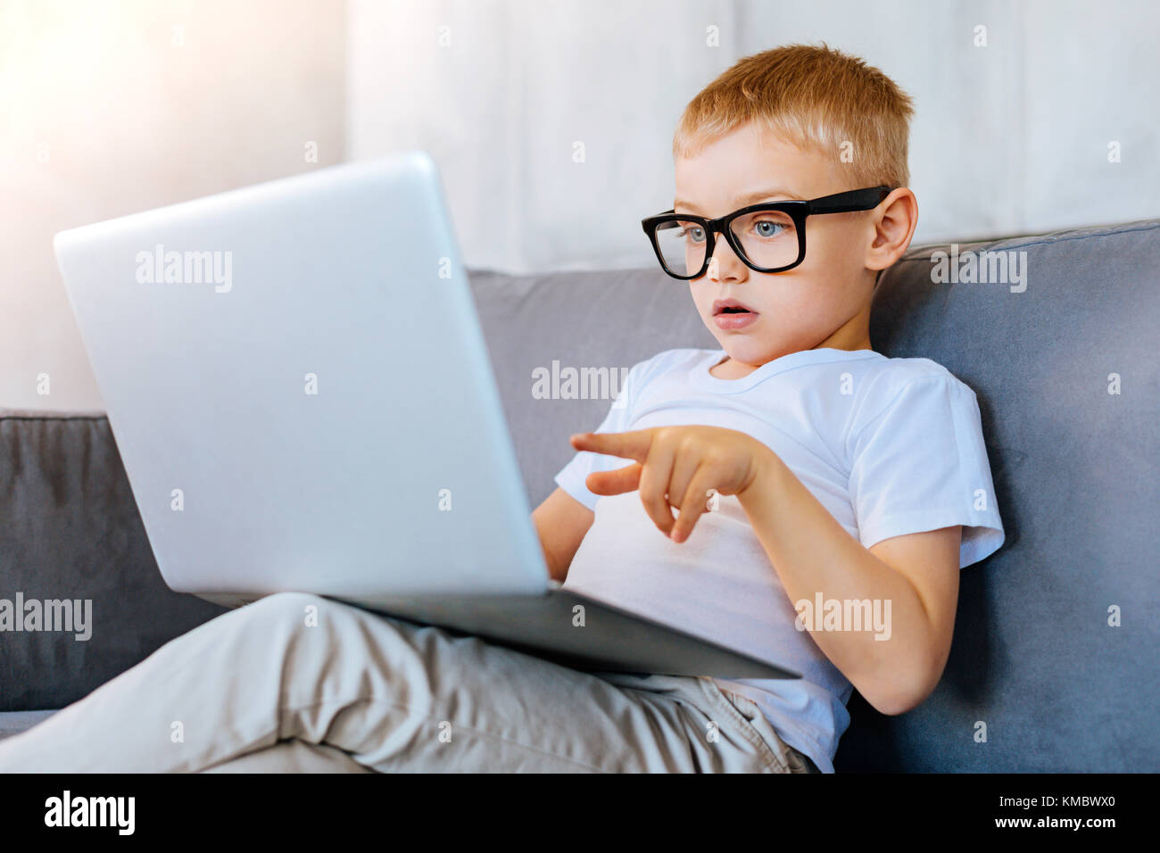 Cute blonde boy pointing at the laptop screen Stock Photo - Alamy