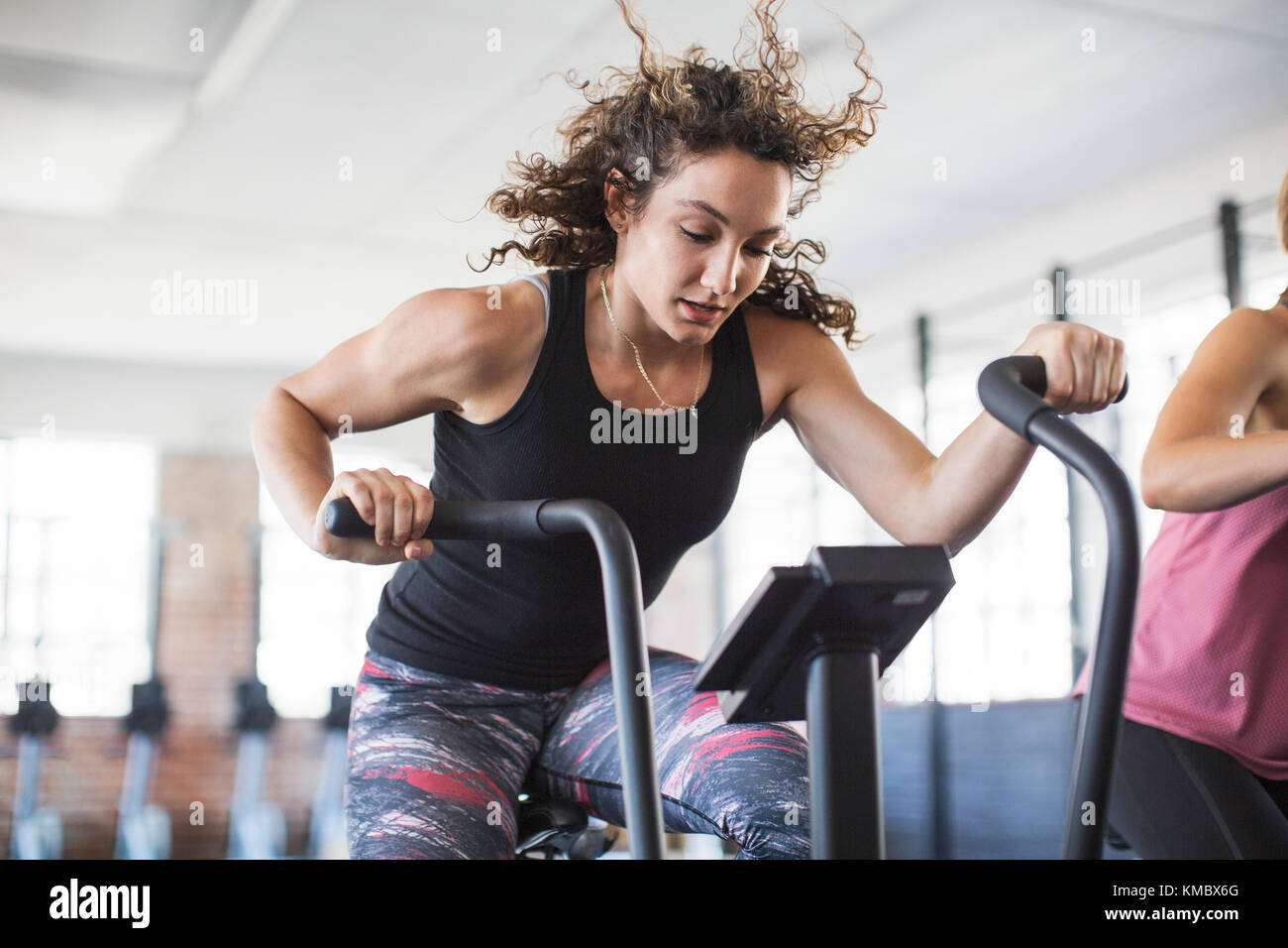 Determined young woman riding elliptical bike in gym Stock Photo - Alamy