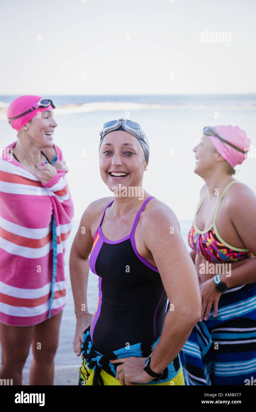Portrait smiling, confident female open water swimmers drying off with ...