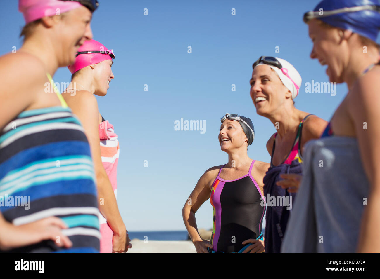 Smiling female open water swimmers talking on sunny beach Stock Photo ...