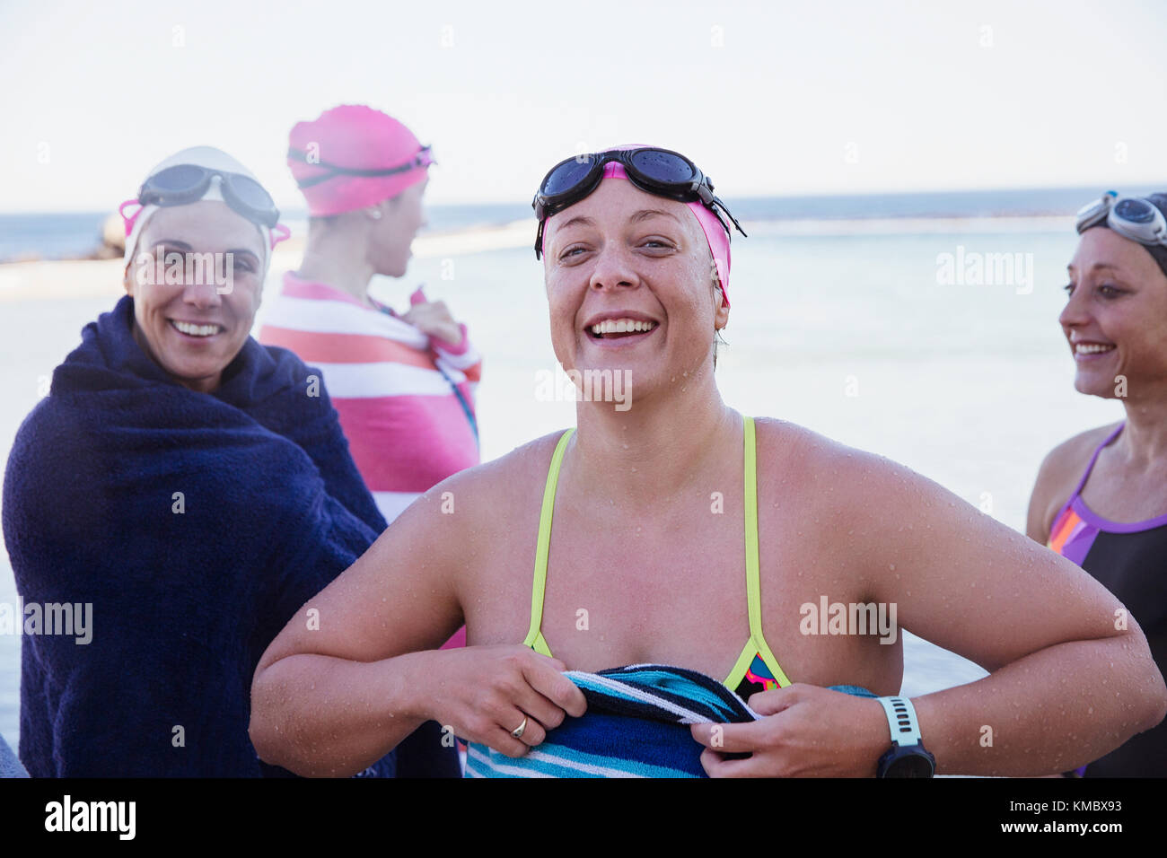 Portrait smiling, confident female open water swimmers drying off with ...
