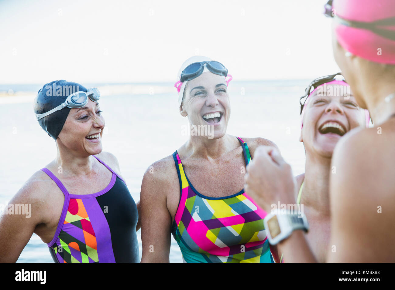 Laughing female open water swimmers talking Stock Photo - Alamy