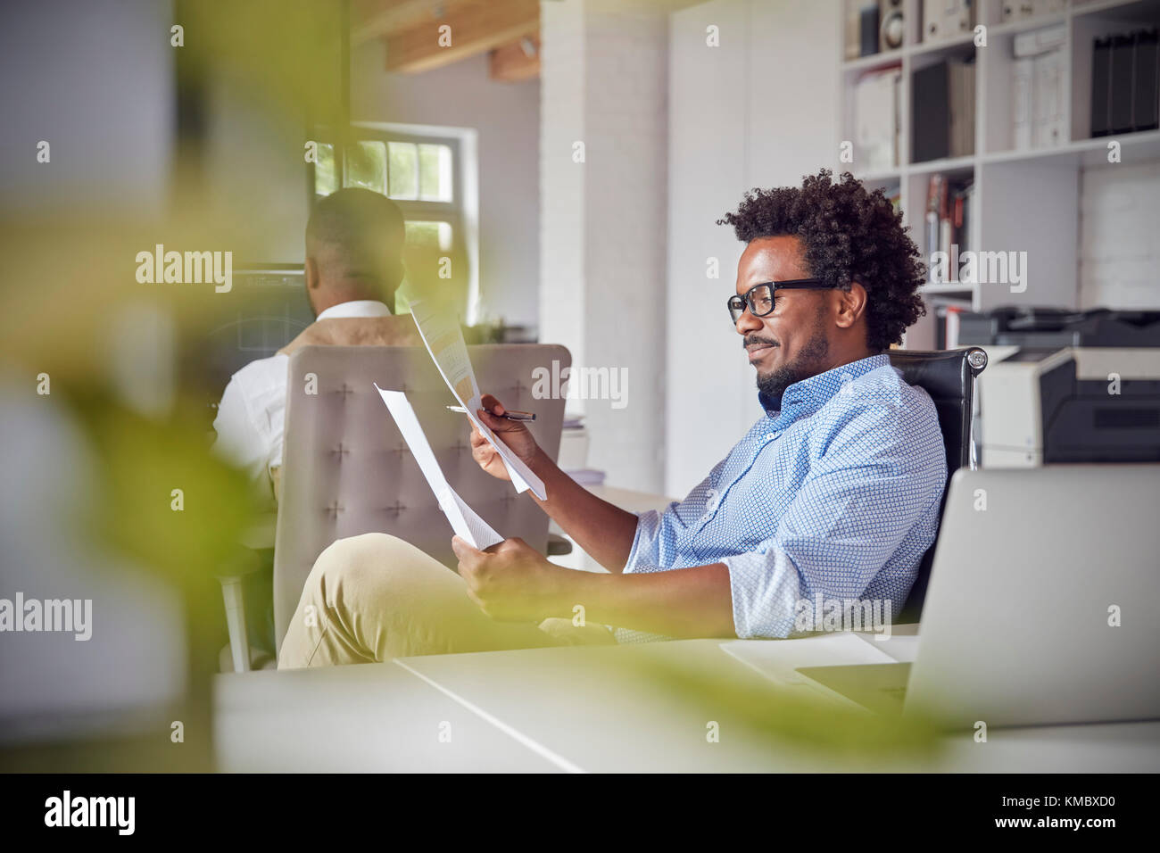 Businessman reading paperwork in office Stock Photo - Alamy