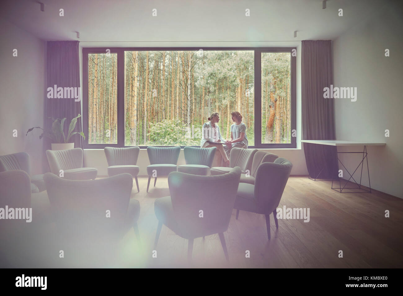 Women talking at window in group therapy room Stock Photo - Alamy