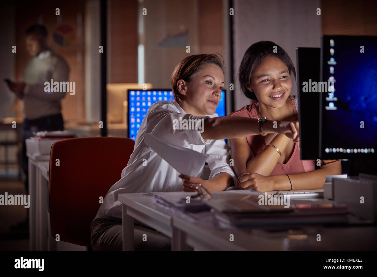Female businesswomen working late at computer in dark office at night ...
