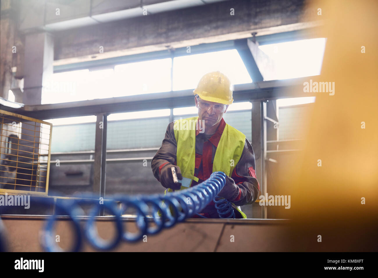 Steelworker using equipment in steel mill Stock Photo - Alamy