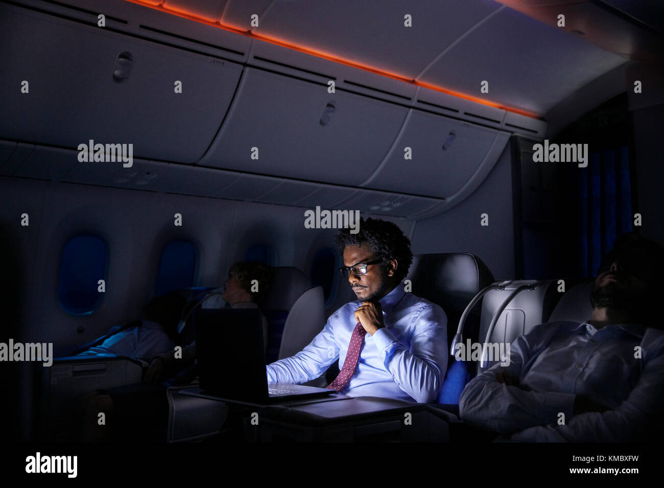 Businessman working at laptop on night airplane Stock Photo - Alamy