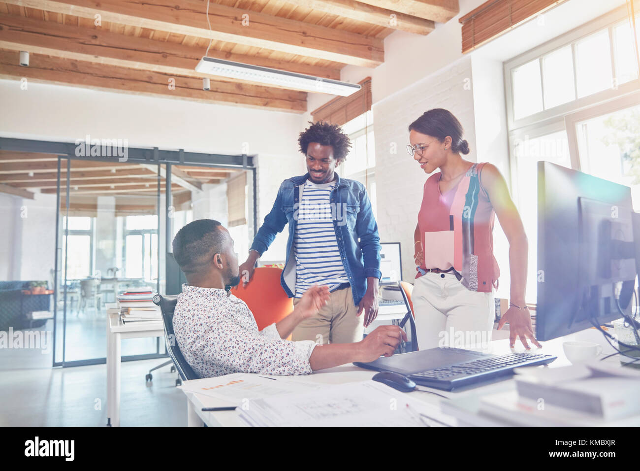 Graphic designers talking at computer with graphics tablet in office ...