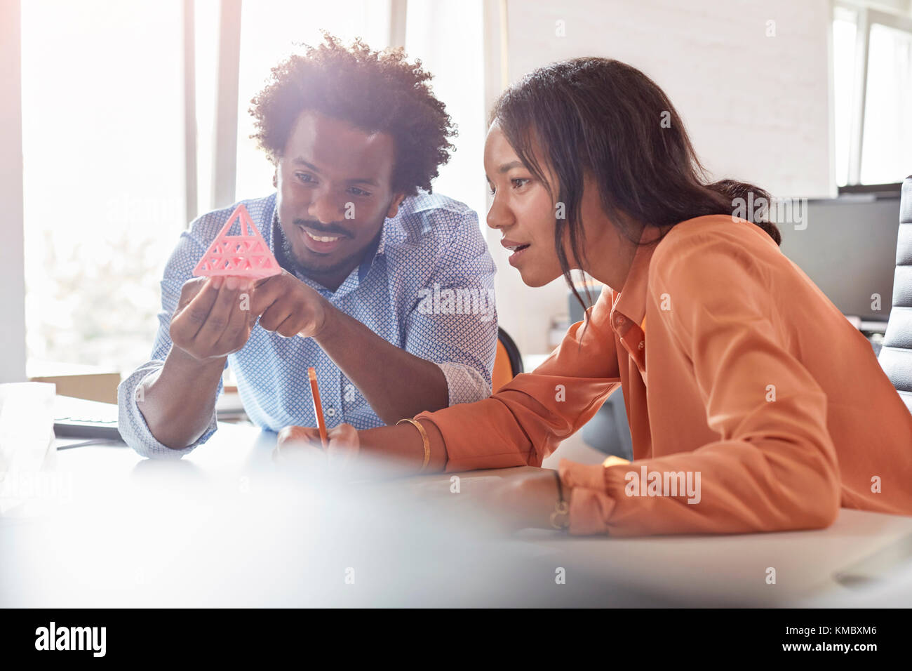 Design professionals examining triangle prototype in office Stock Photo ...