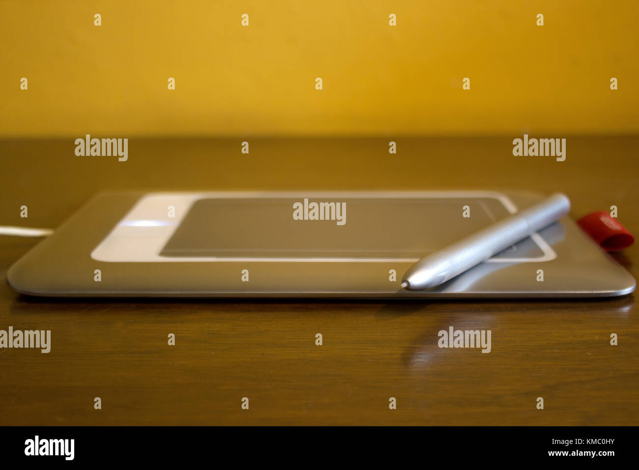 Horizontal photo of a silver pen tablet on a brown wood table Stock ...