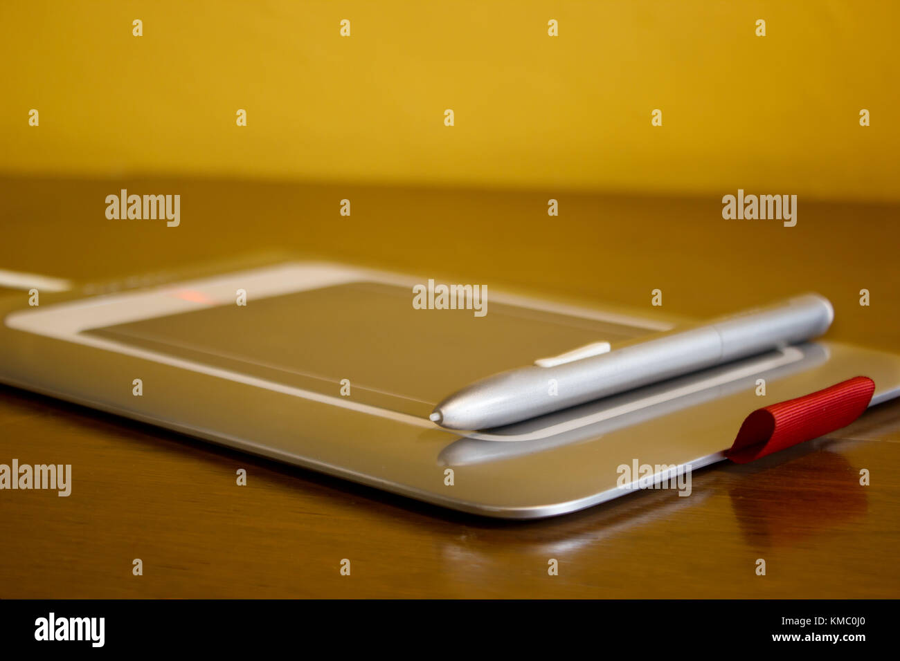 Horizontal photo of a silver pen tablet on a brown wood table rich in ...