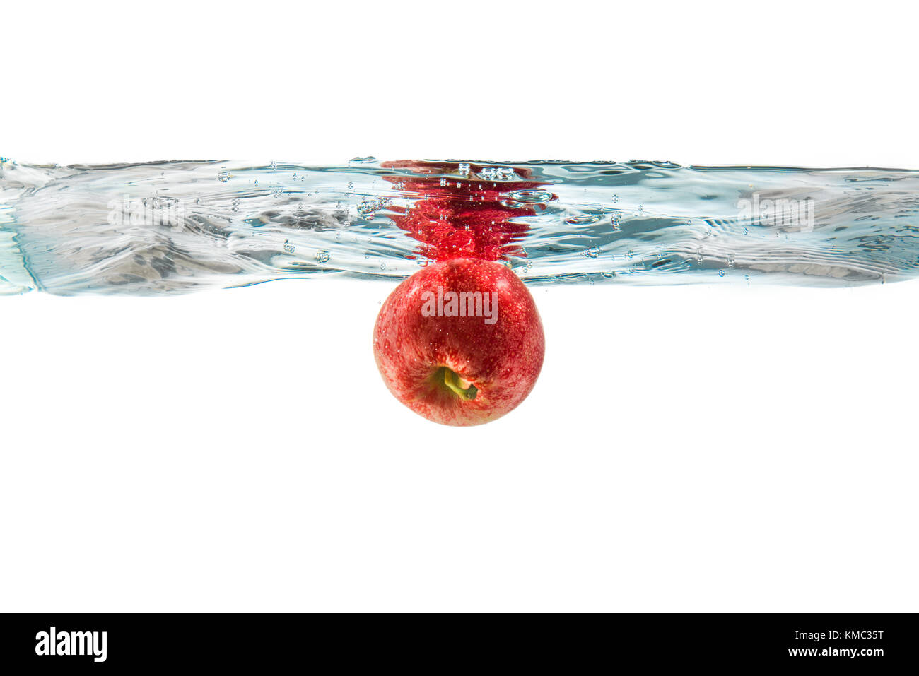 Red apple dropped into the water with water splash on a white ...