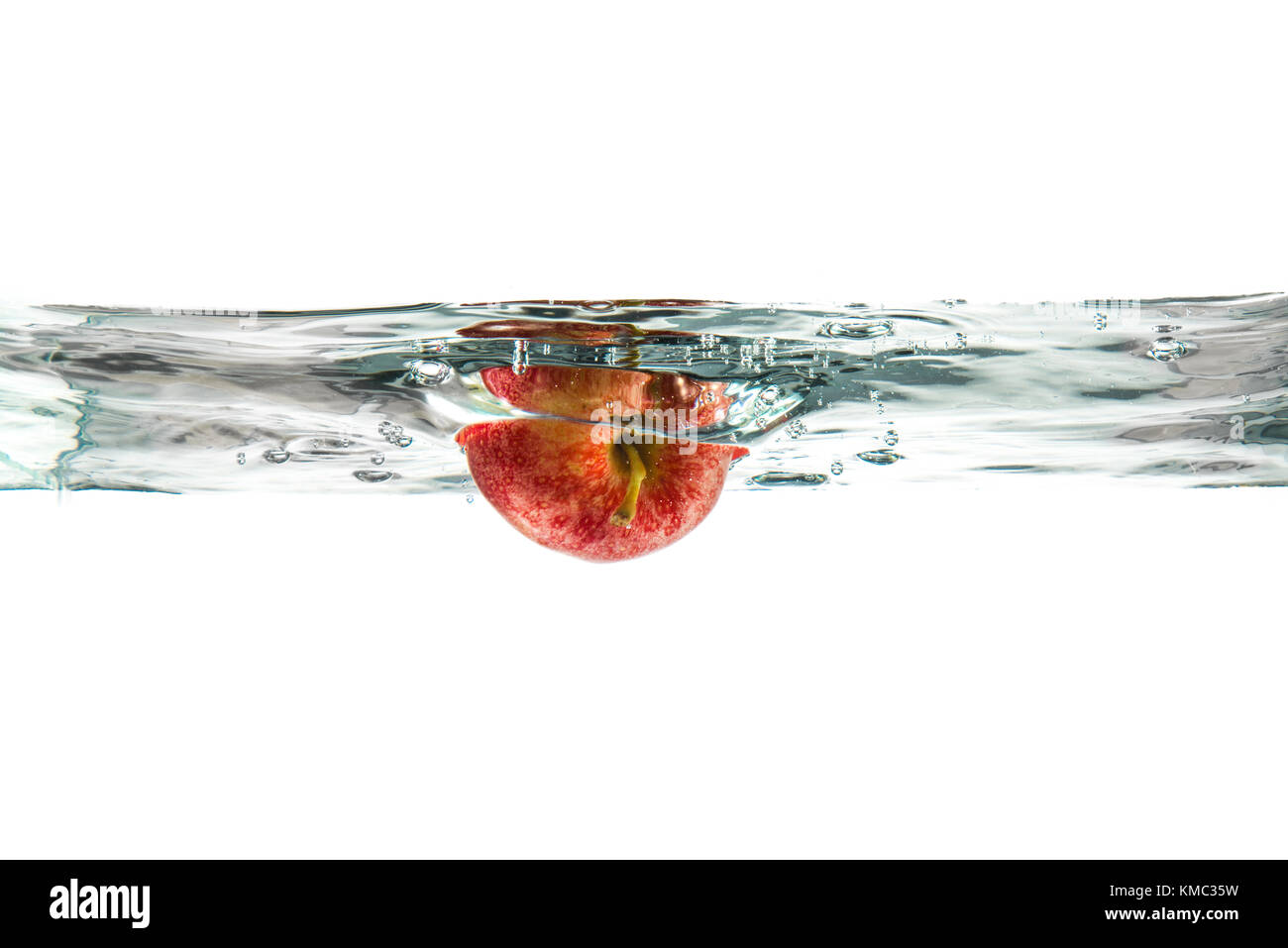Red apple dropped into the water with water splash on a white ...